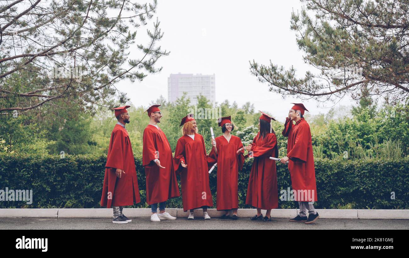 happy graduates laughing and celebrating graduation on college campus ...