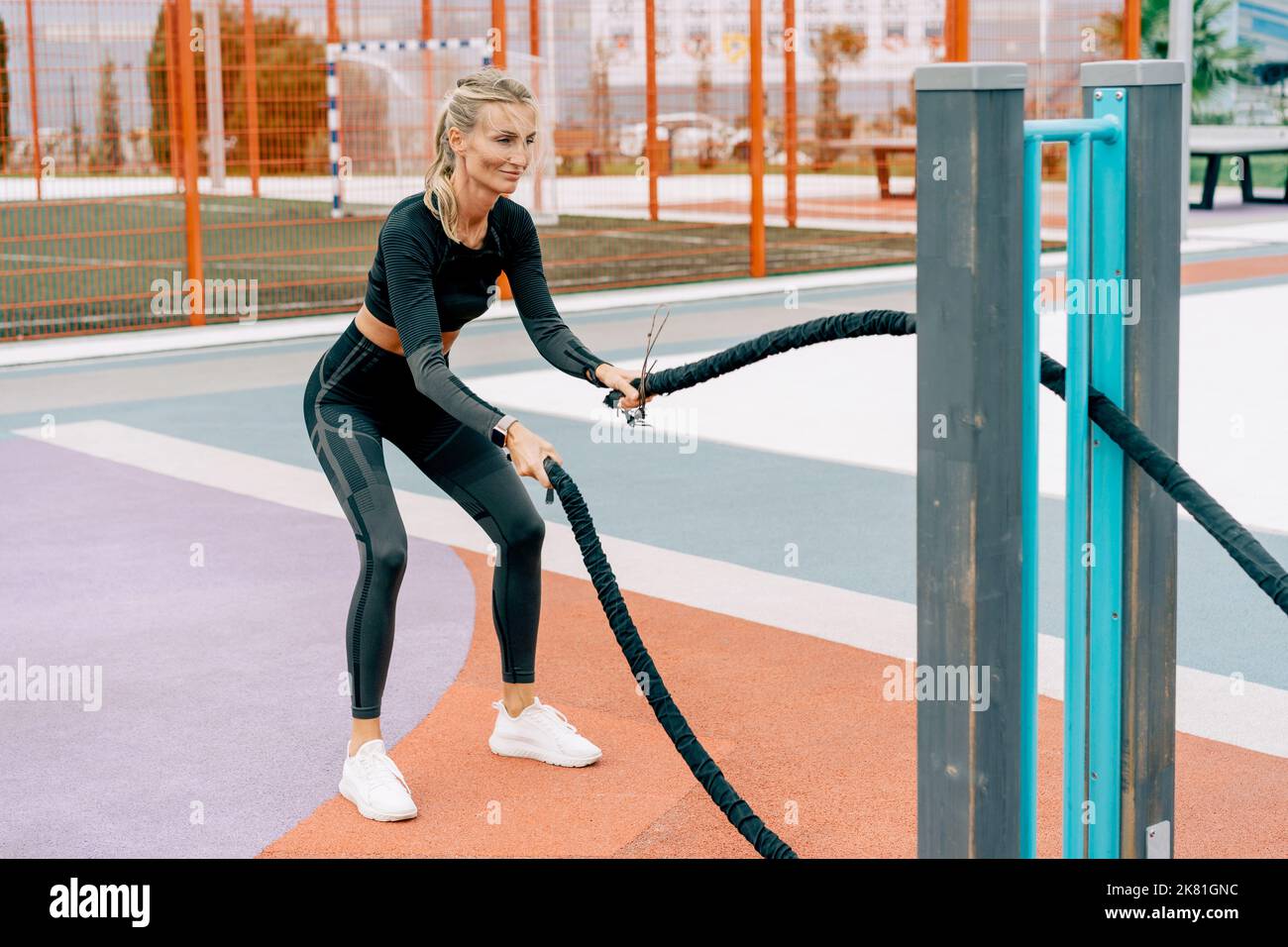 A woman trains on battle ropes on the sports ground Stock Photo - Alamy