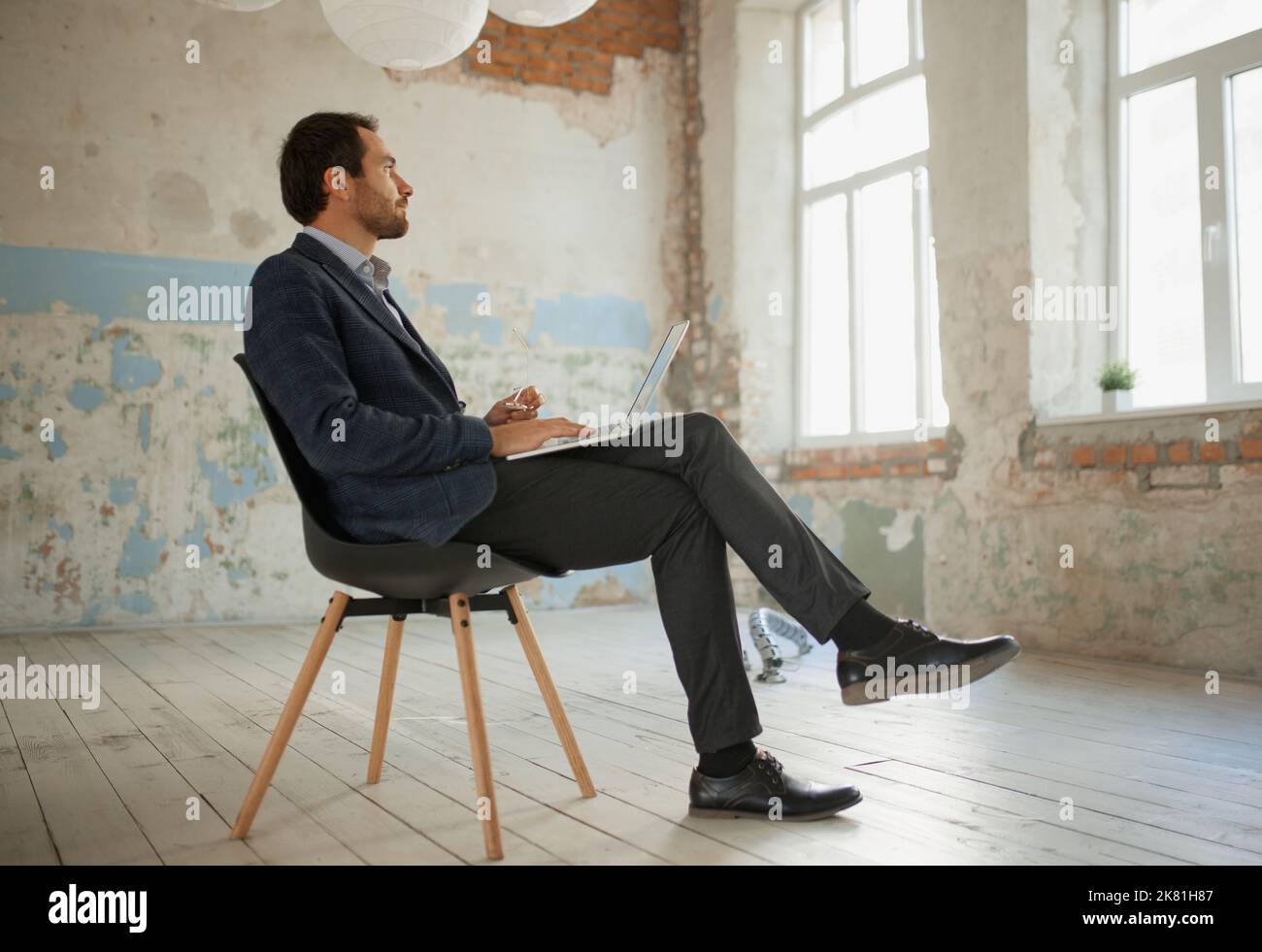 Portrait of young businessman sitting on chair in empty room and ...