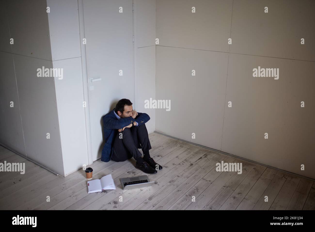 Portrait of young businessman sitting on floor in empty room. Business ...