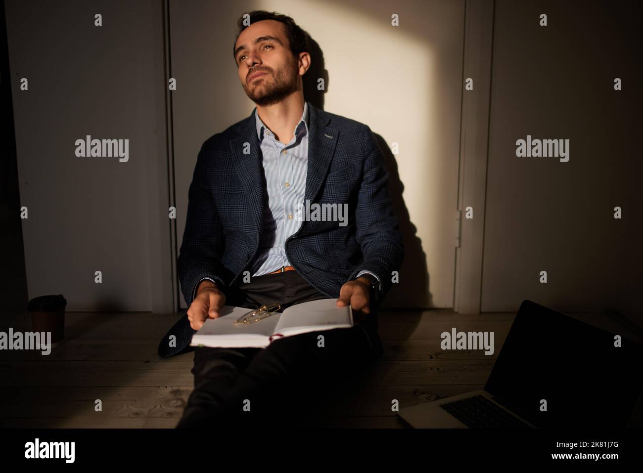 Portrait of young businessman sitting on floor in empty room. Business ...