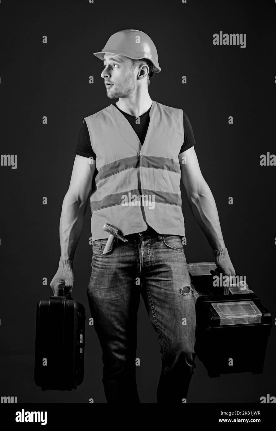 Professional repairman concept. Man in helmet, hard hat holds toolbox ...