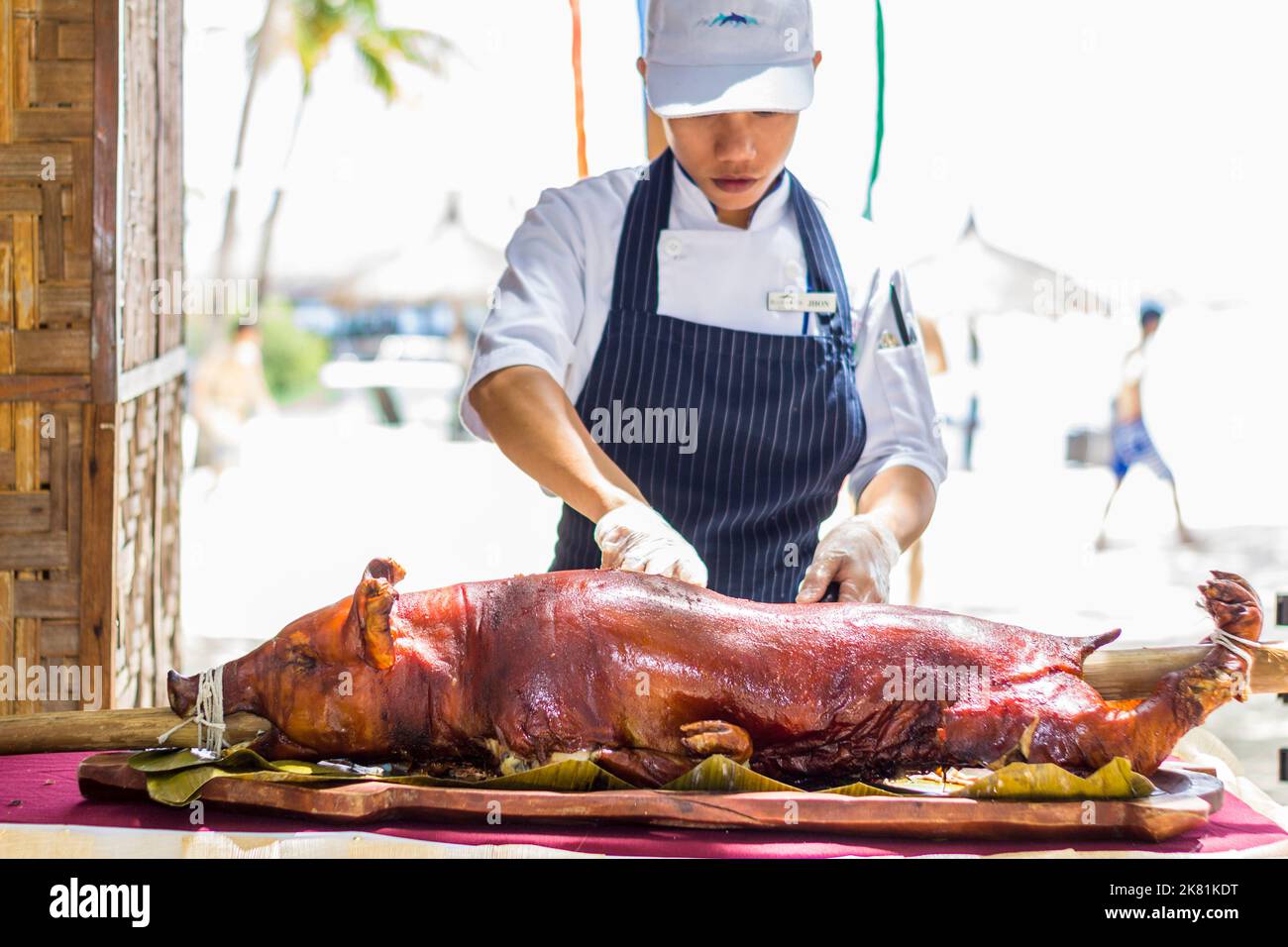 A restaurant staff slices a portion of a whole Filipino lechon or roast pig in Cebu, Philippines ...