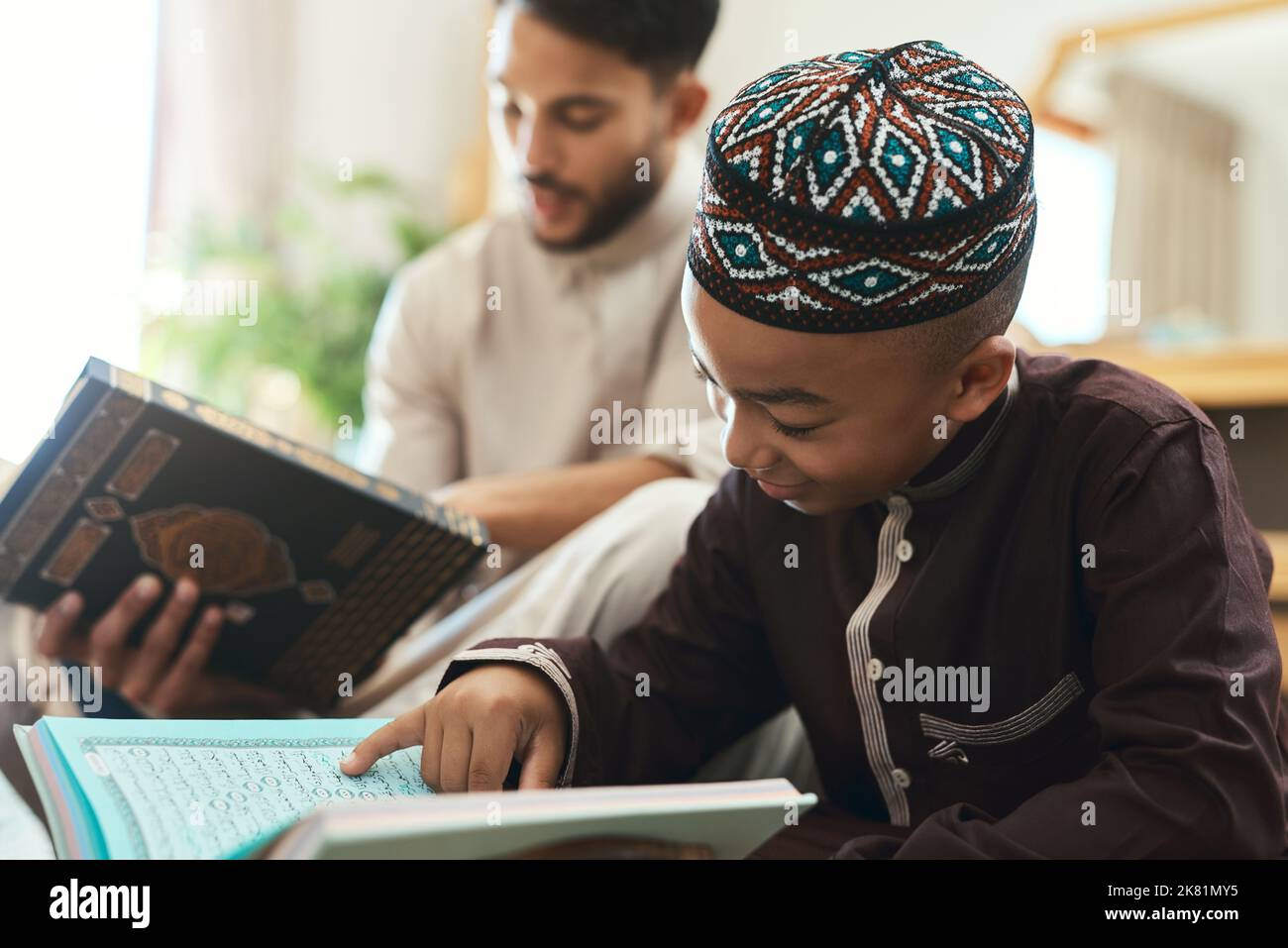 Like father, like son. a young muslim man and his son reading in the ...
