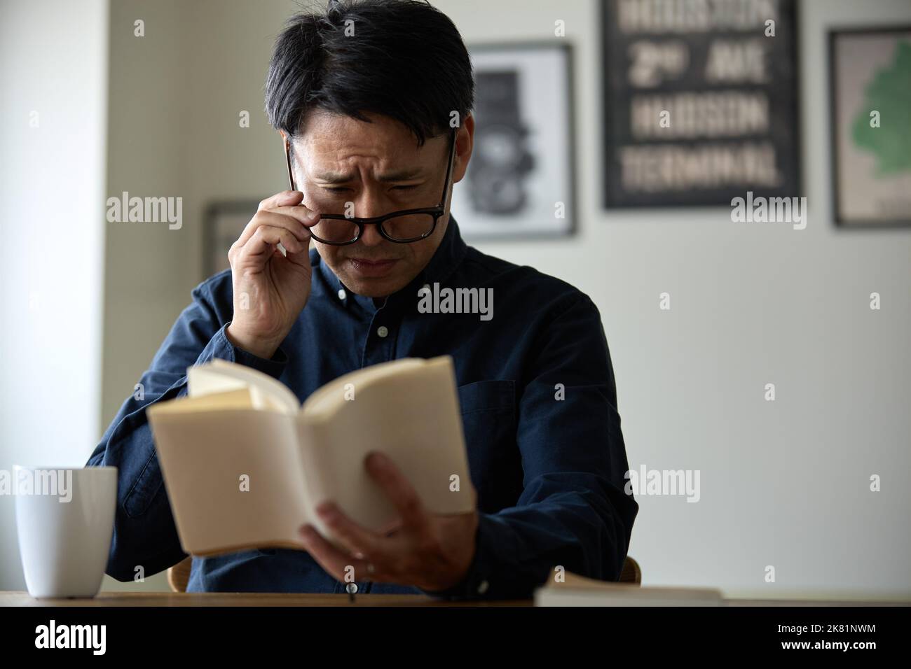 Japanese man with presbyopia reading a book Stock Photo - Alamy