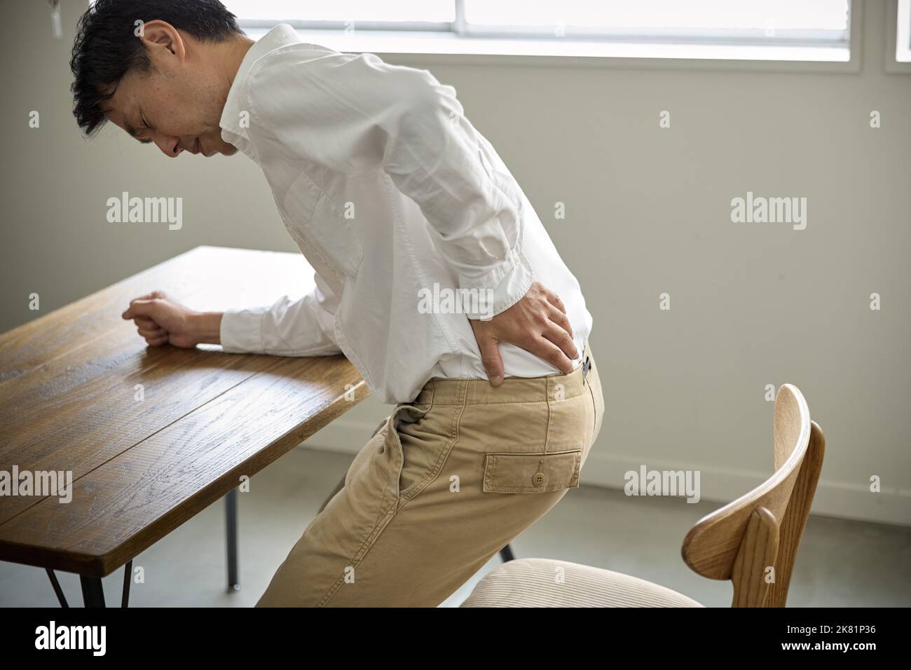 Japanese man with back pain at home Stock Photo - Alamy