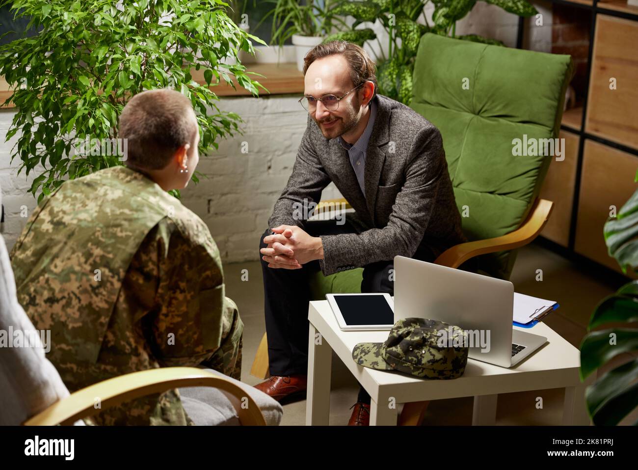 Two people, soldier in military uniform and psychologist at therapy ...