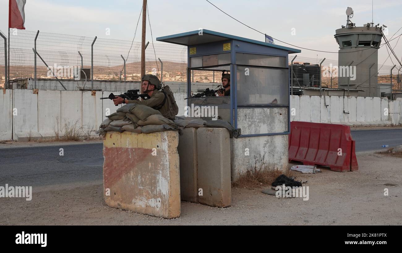 Israeli soldiers aim their weapon as they stand guard behind concrete ...