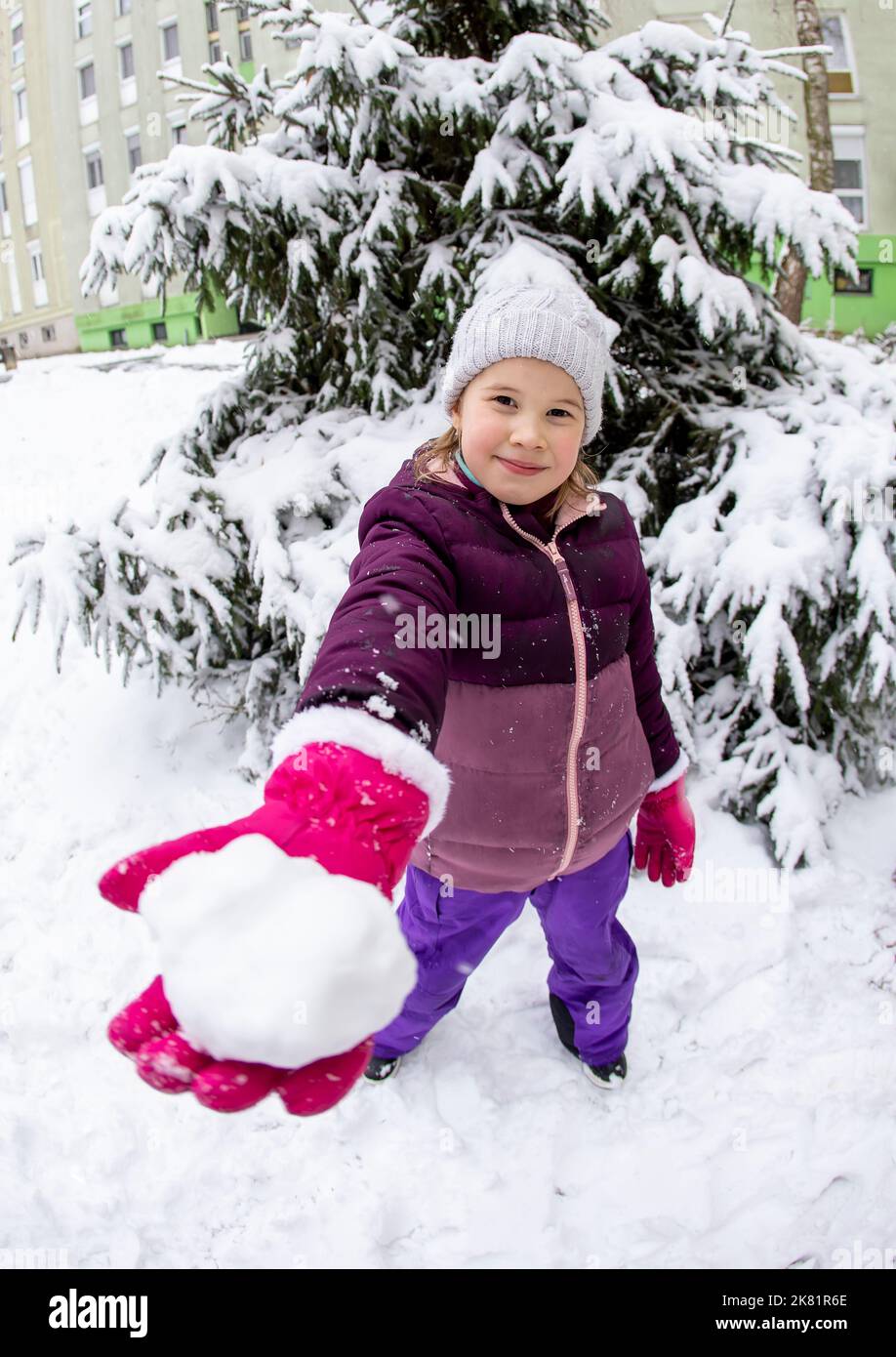 Cute beautiful smiling girl with snowball outdoor in snow in wintertime ...