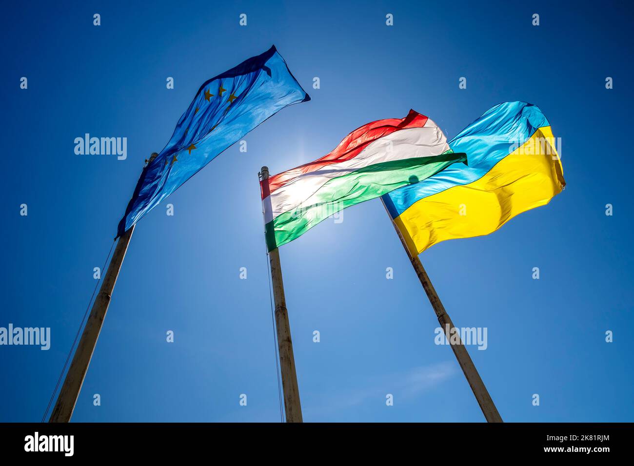 Flags of Hungary Ukraine and European Union waving on pole against blue ...
