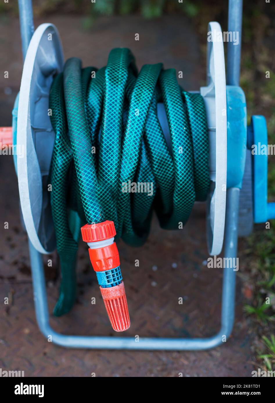 Garden hose rolled up on holder Stock Photo - Alamy