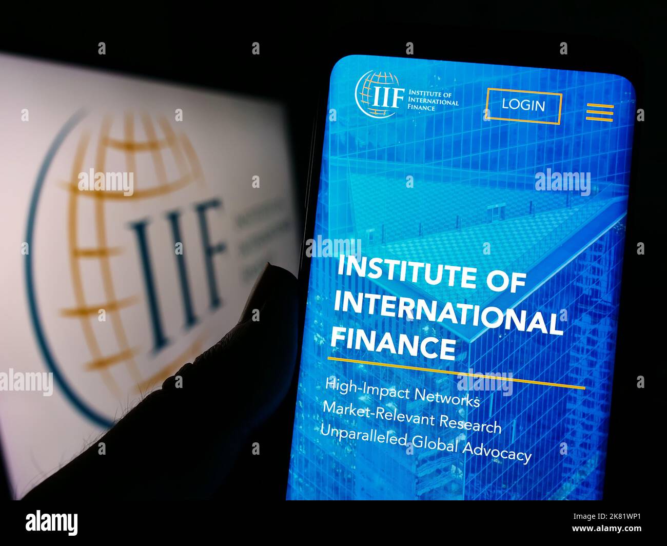 Person holding mobile phone with website of Institute of International ...