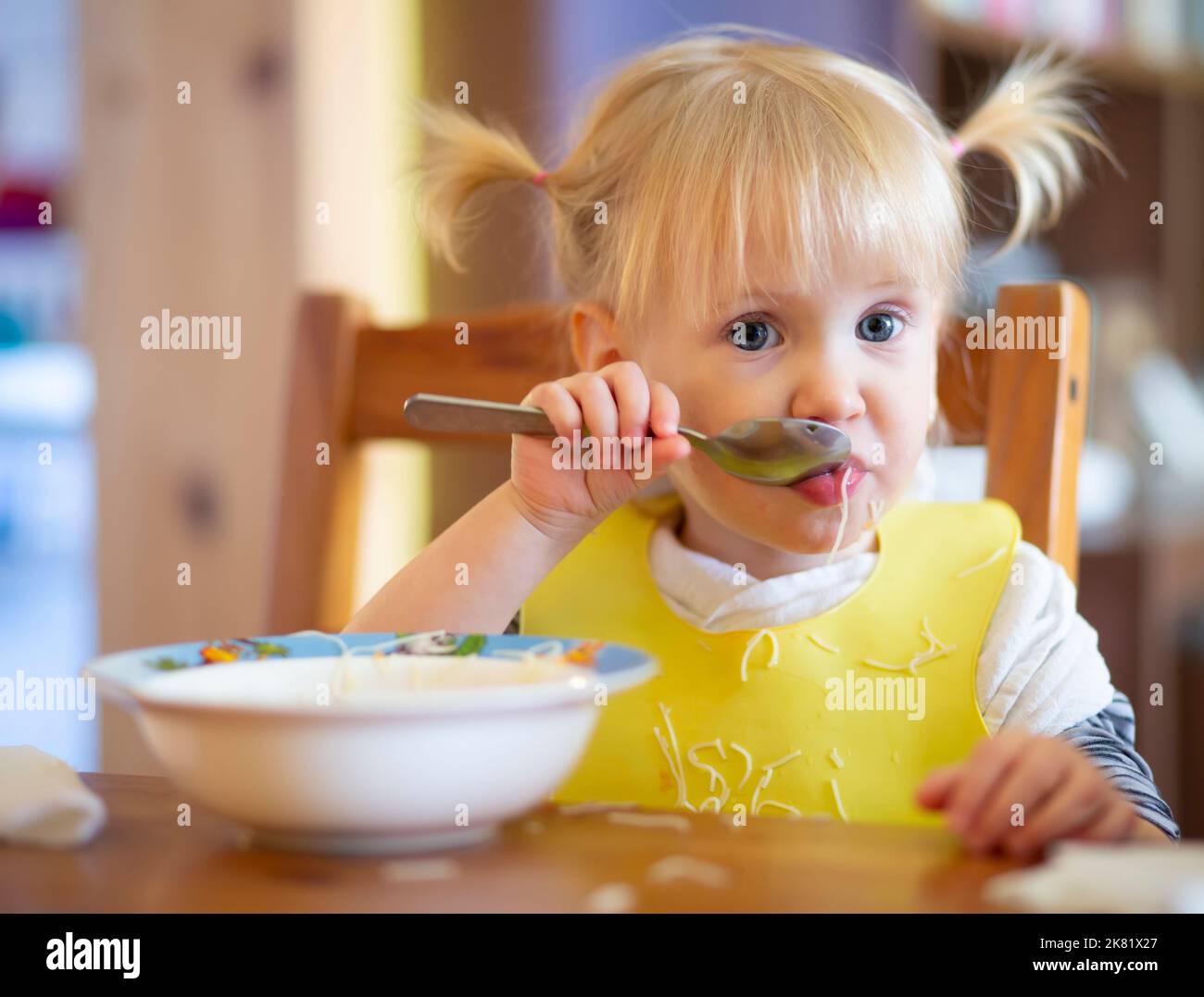 Cute child eating with spoon at table Stock Photo - Alamy