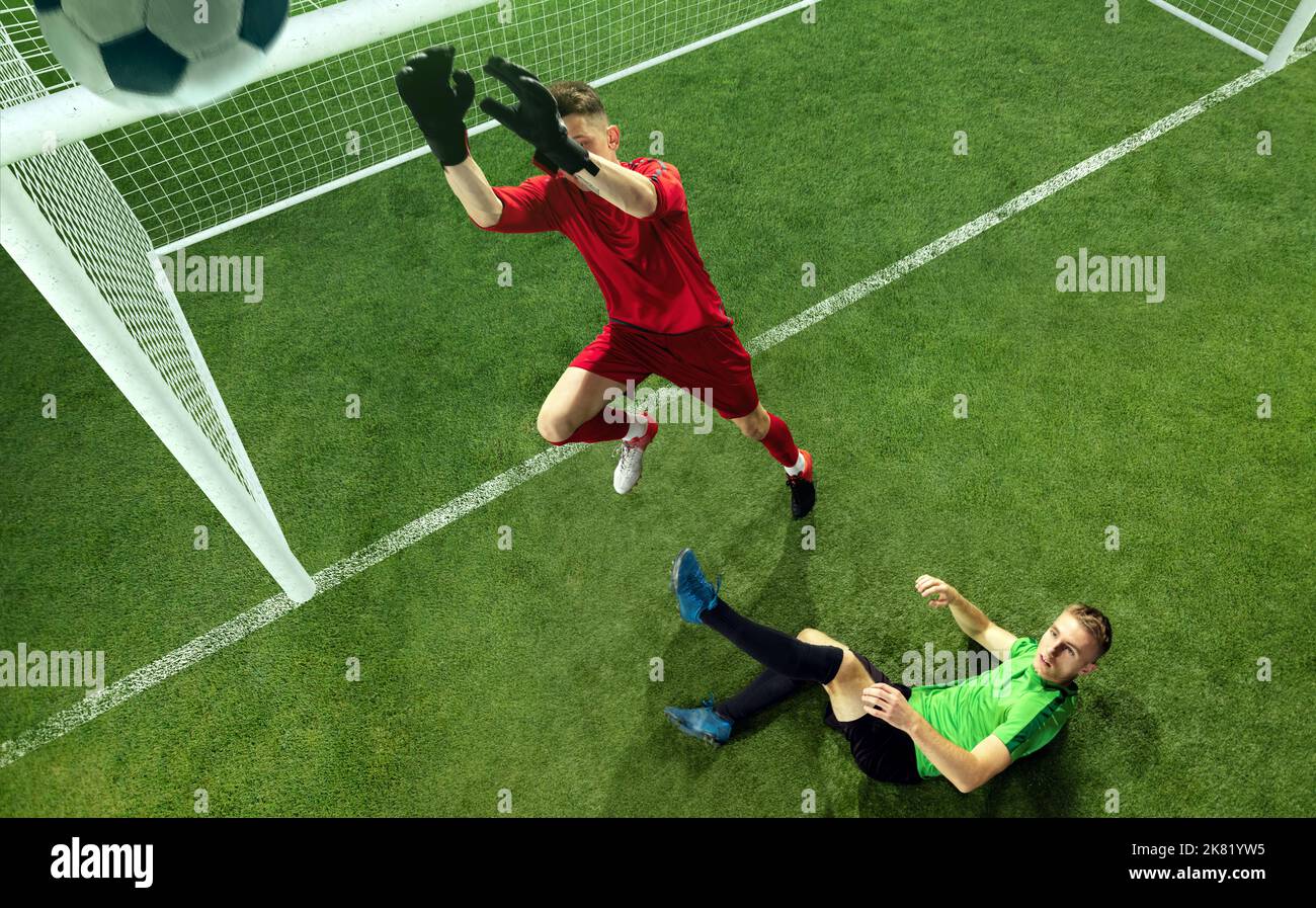 Male soccer player goalkeeper catching ball in jump. Sport competition ...