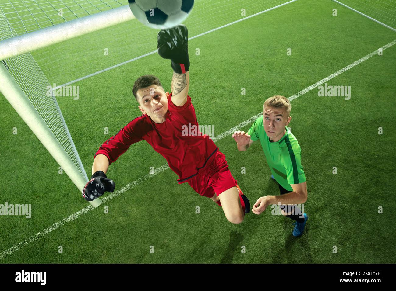 Soccer goalkeeper in action on soccer stadium. Goalkeeper hits the ball ...