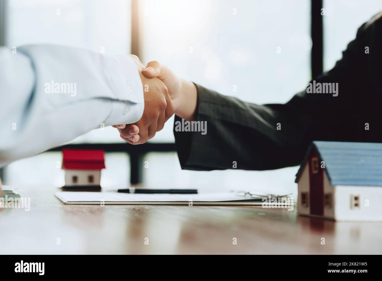 Real estate agents shake hands with customers after signing documents ...