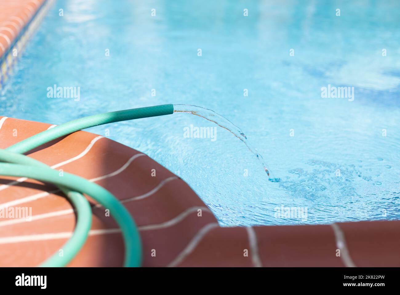 Water pipe filling up swimming pool, closeup. Pool maintenance ...