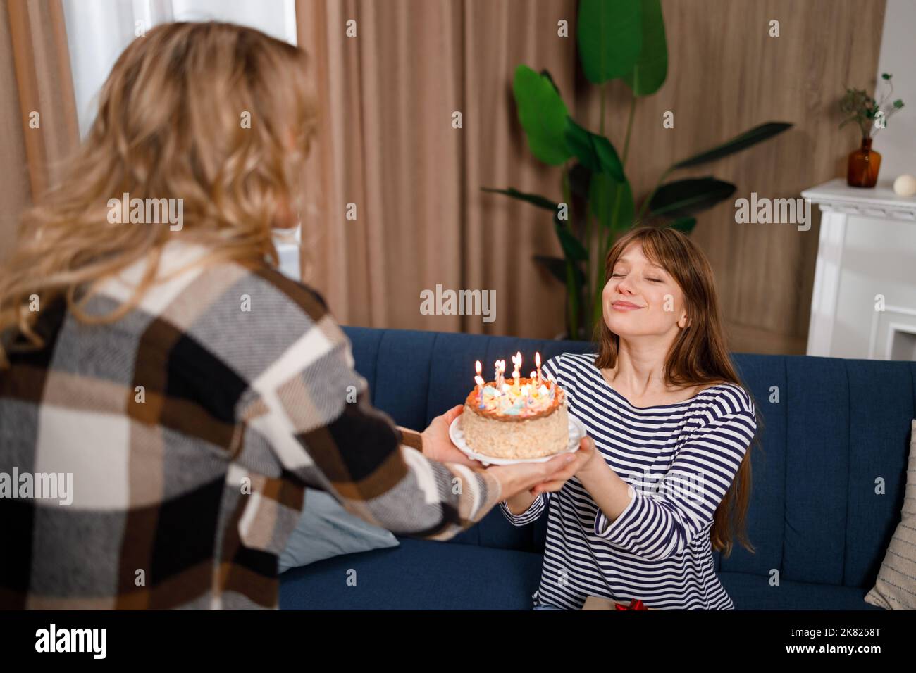 Birthday woman with closed eyes makes a wish and prepares to blow out ...