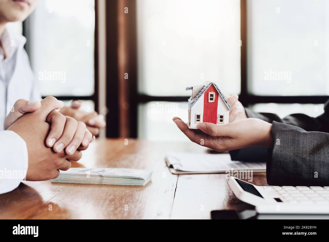 The real estate agent is showing the house model to the customer Stock ...