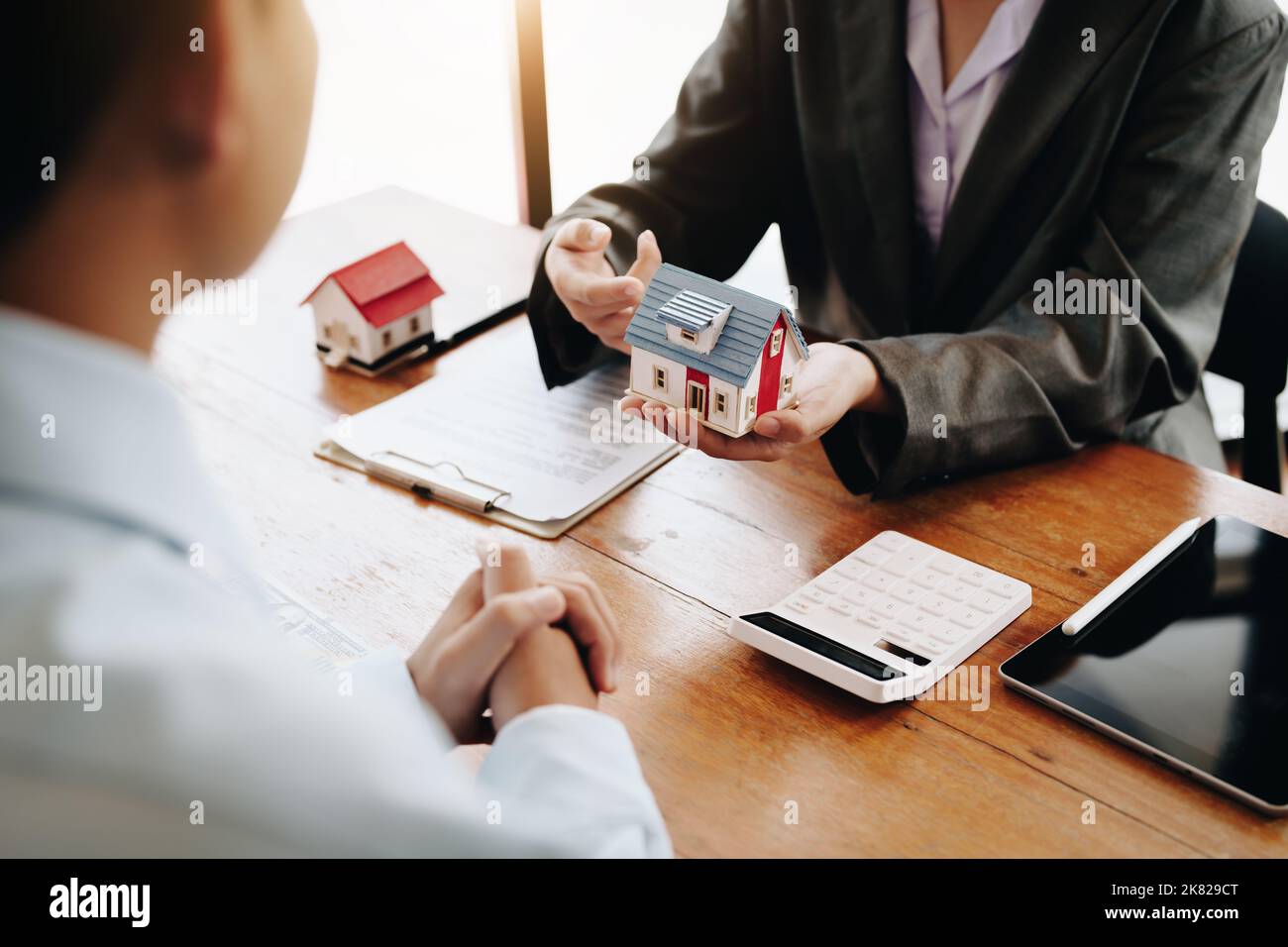 The real estate agent is showing the house model to the customer Stock ...