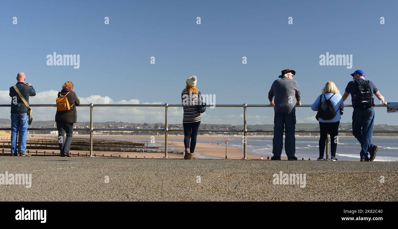 People standing beside railings on the seafront at Dawlish Warren ...