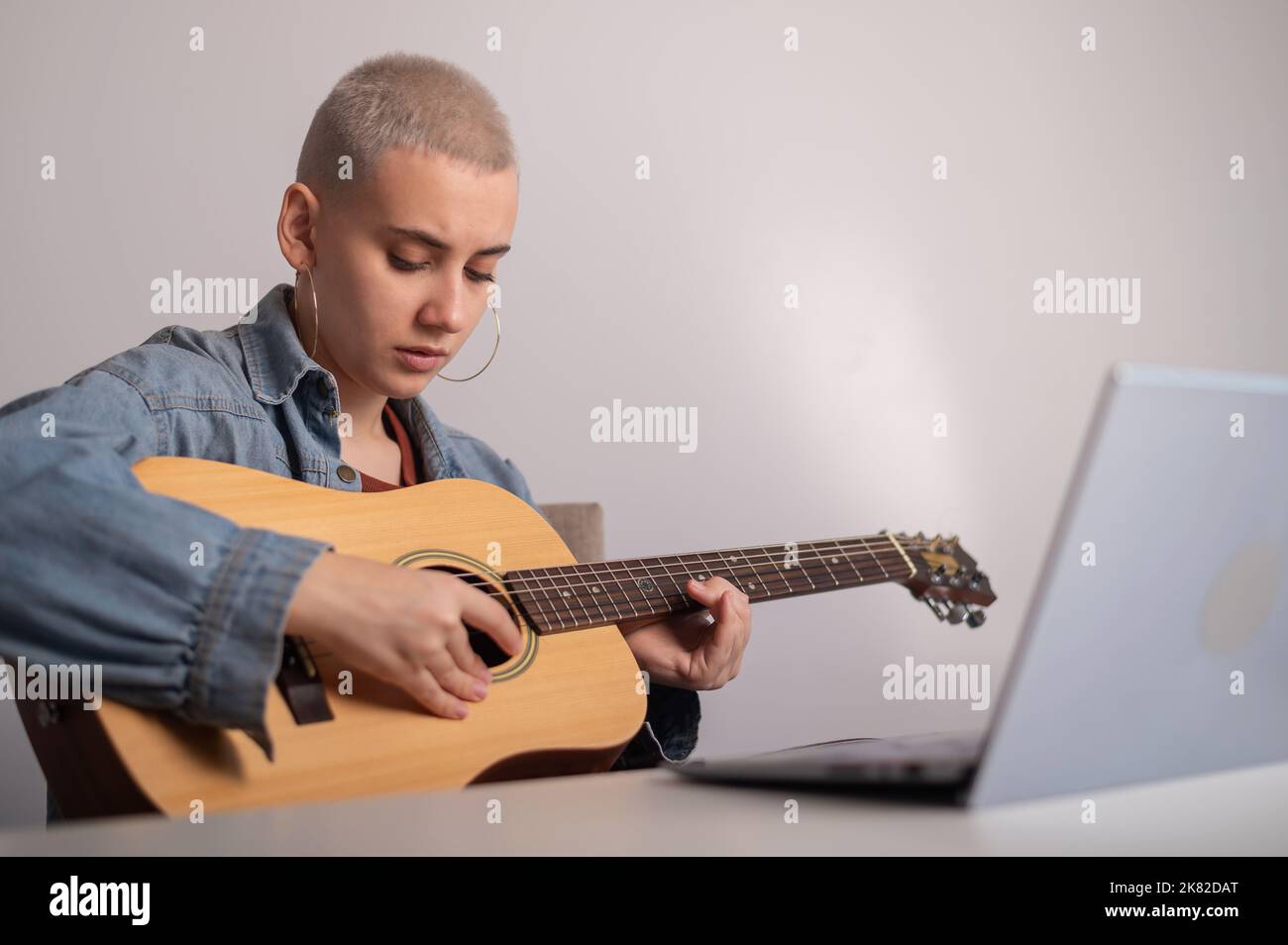 Young caucasian woman with short blonde hair playing guitar and ...