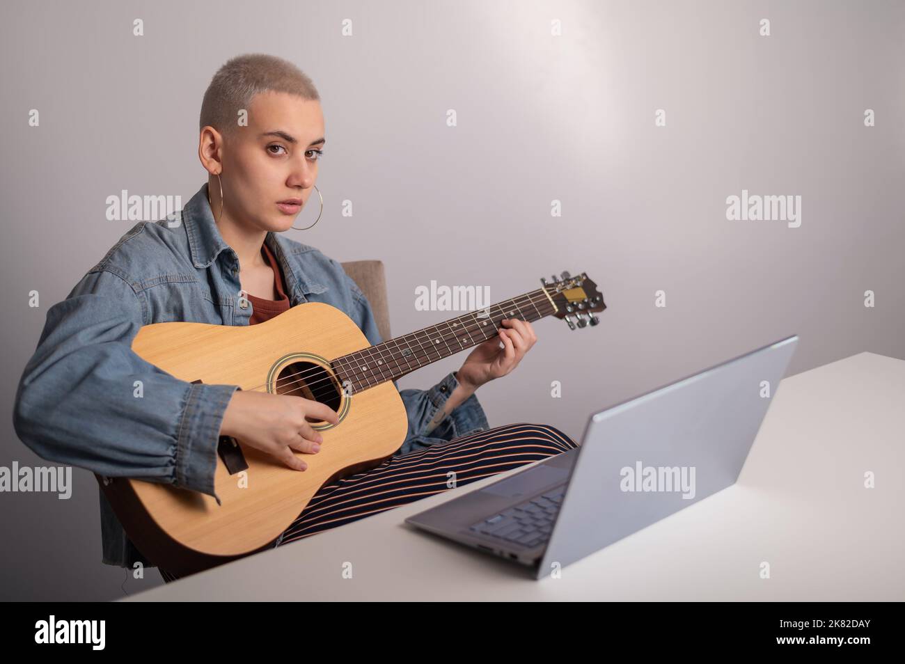 Young caucasian woman with short blonde hair playing guitar and ...