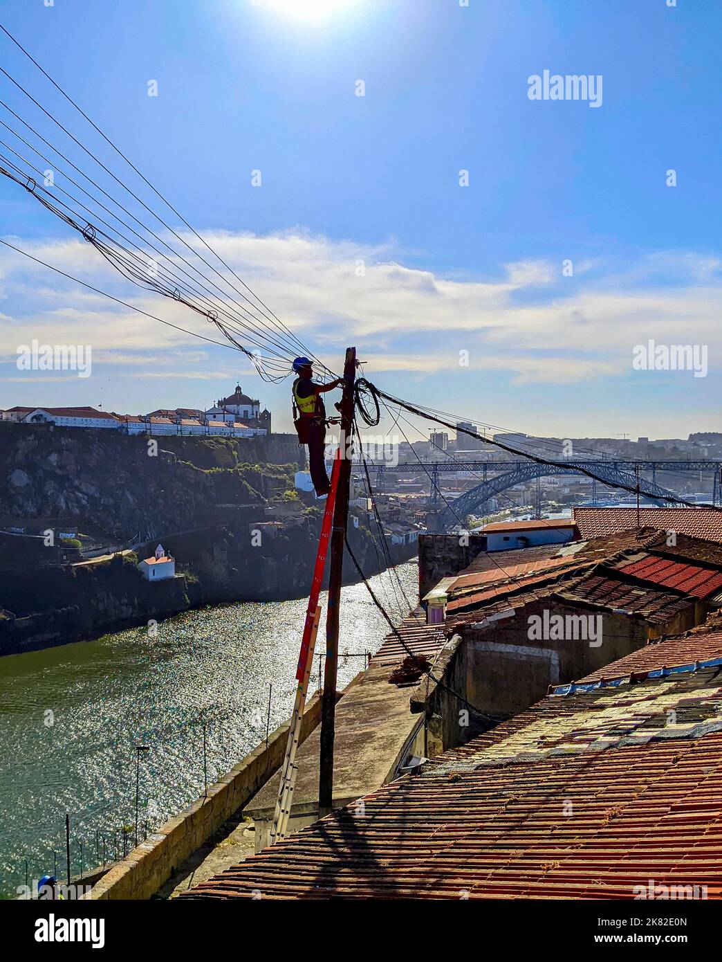 Electricity service worker fixinig wires, aerial cityscape in bright ...