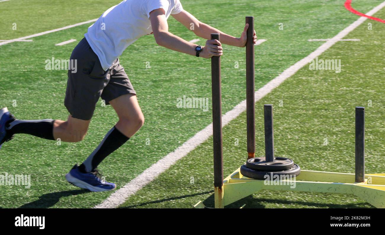 A high school runner at speed and strength summer camp is pushing a ...
