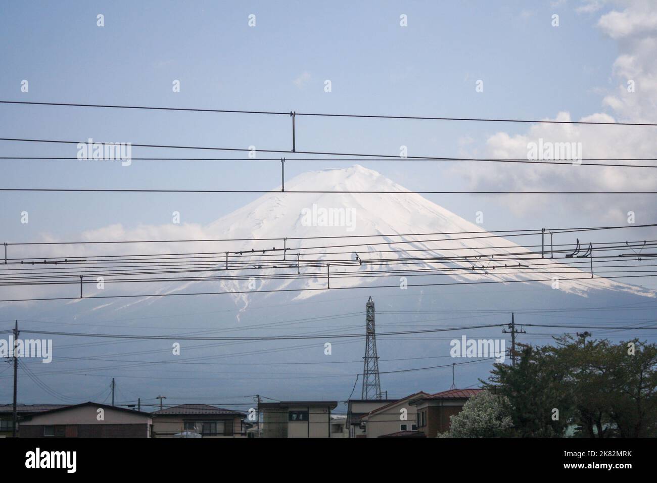 View of Mount Fuji from train station with houses and clouds in blue ...