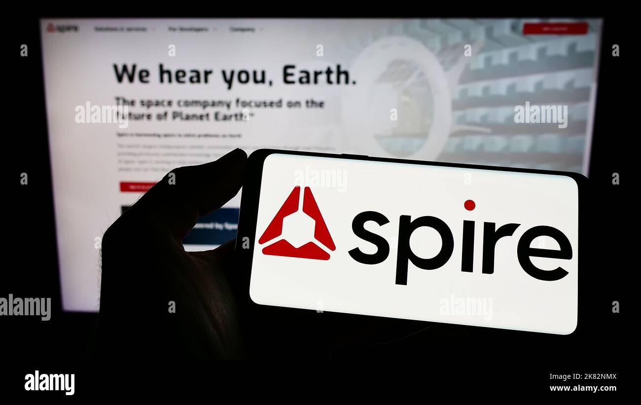 Person holding smartphone with logo of US data analytics company Spire Global Inc. on screen in ...