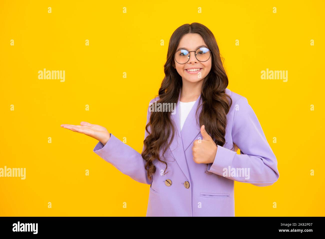 Positive teenager child points aside with cheerful expression, shows ...