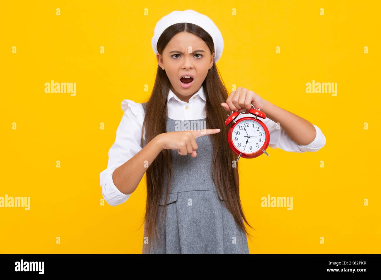 Teen student girl hold clock isolated on yellow background. Time to ...