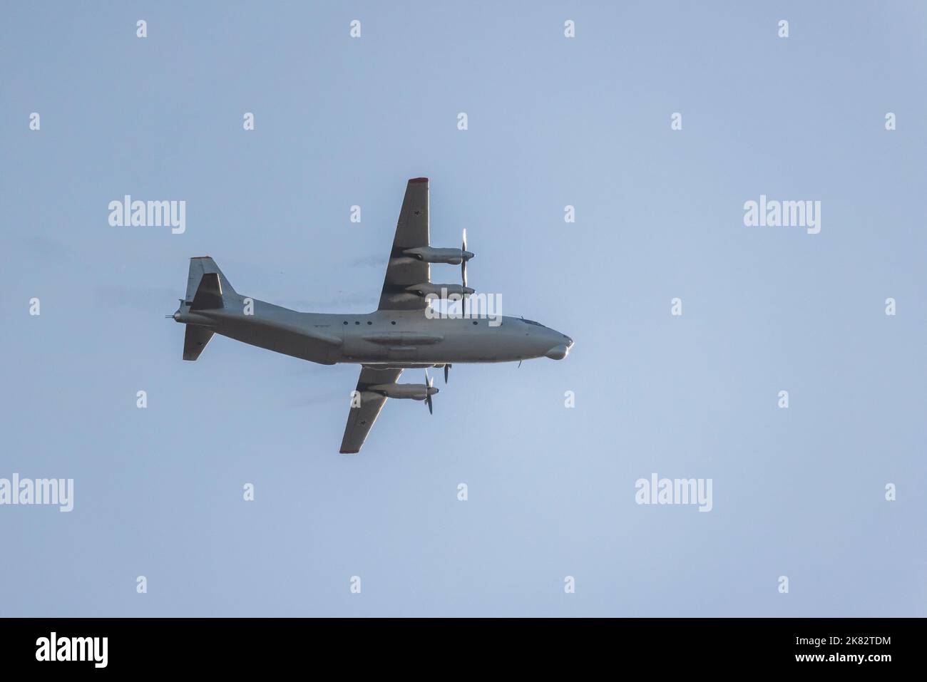 Four-engined turboprop transport aircraft is in blue sky on a daytime ...