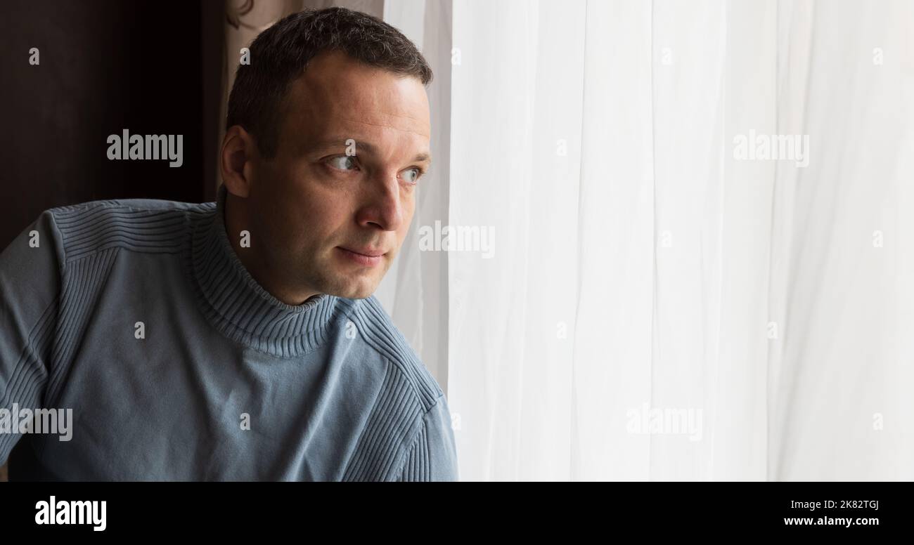 Close up portrait of young adult European man staring out the window ...