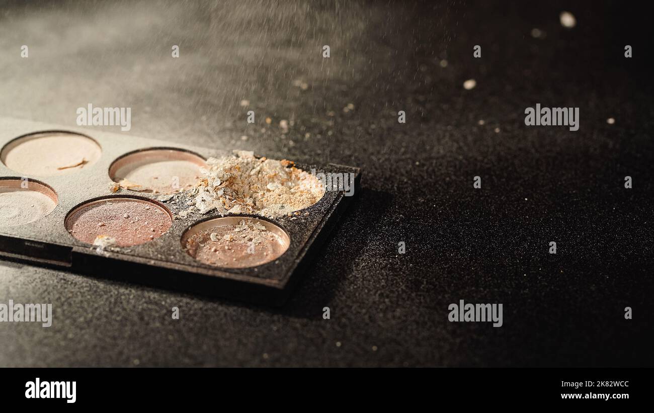 Palette with crushed face powder on black background with copy space ...