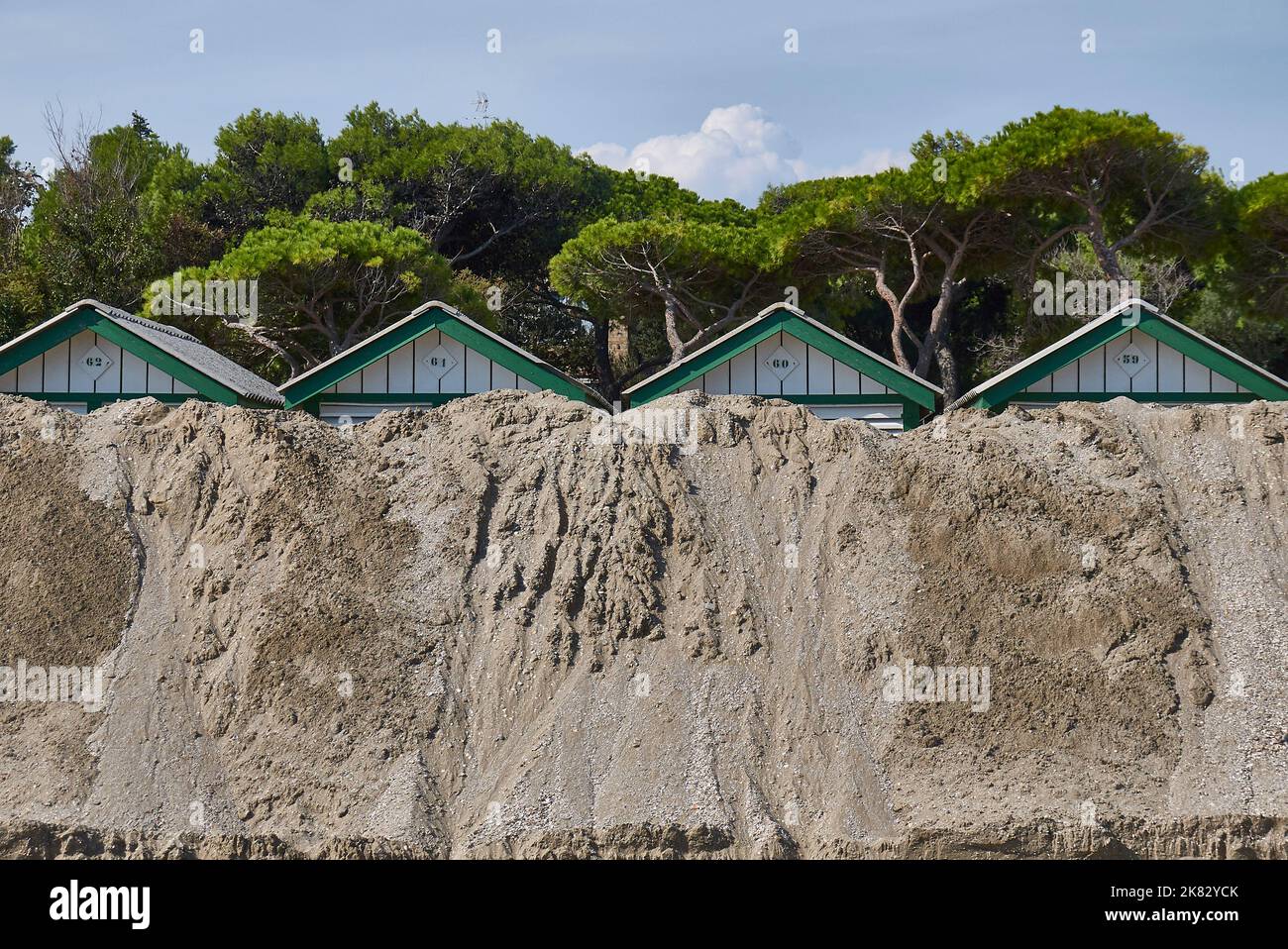 A row of beach huts concealed by a sandhills. Only the gables and roofs ...