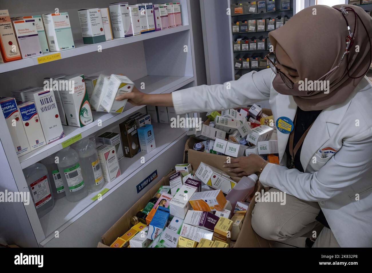 A pharmacist unloads a line of syrup-type drugs from a sales shelf at a ...