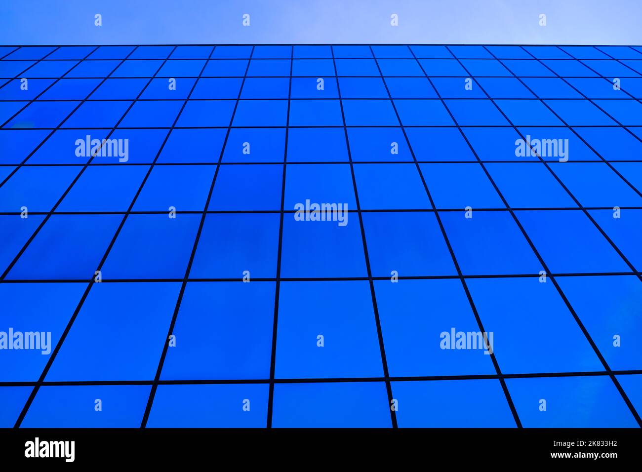 Business building with reflective glass windows reflecting blue sky ...