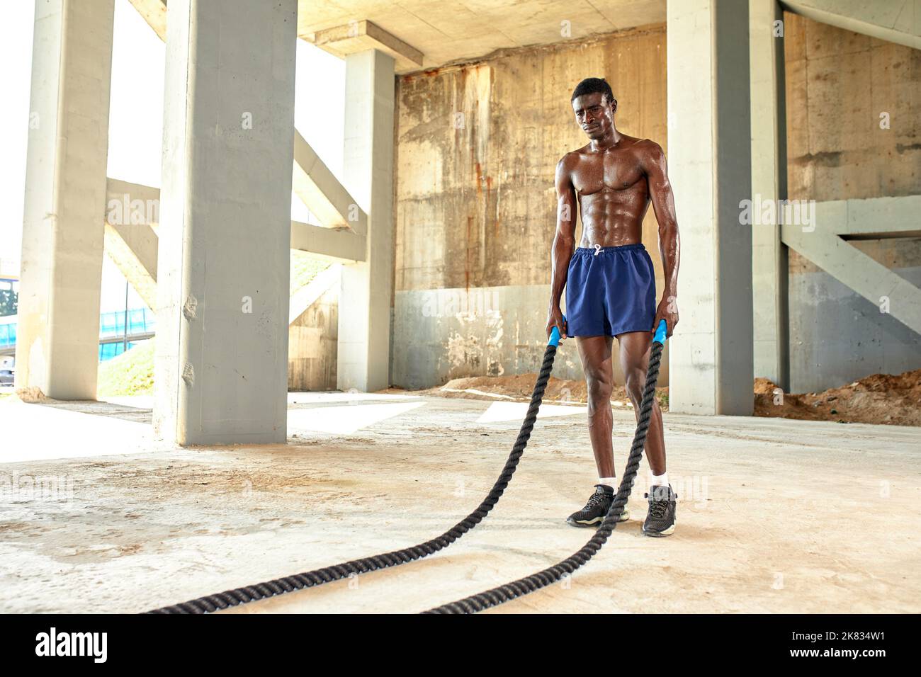 Rope workout. Sport man doing battle ropes exercise outdoor. Black male ...