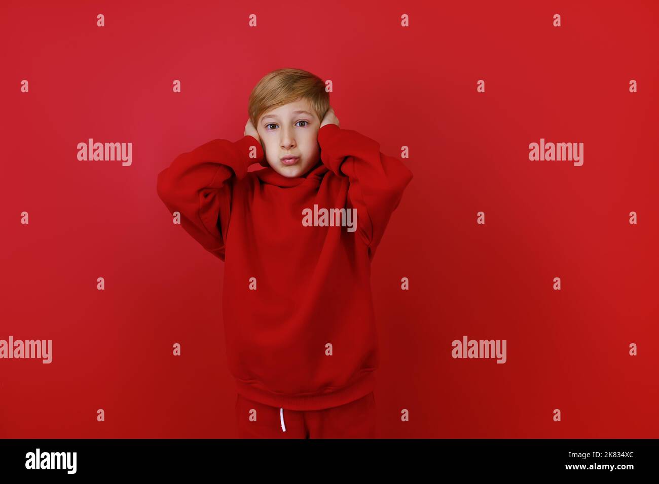 on a red background stands a boy dressed in a red suit, he clutched his ...