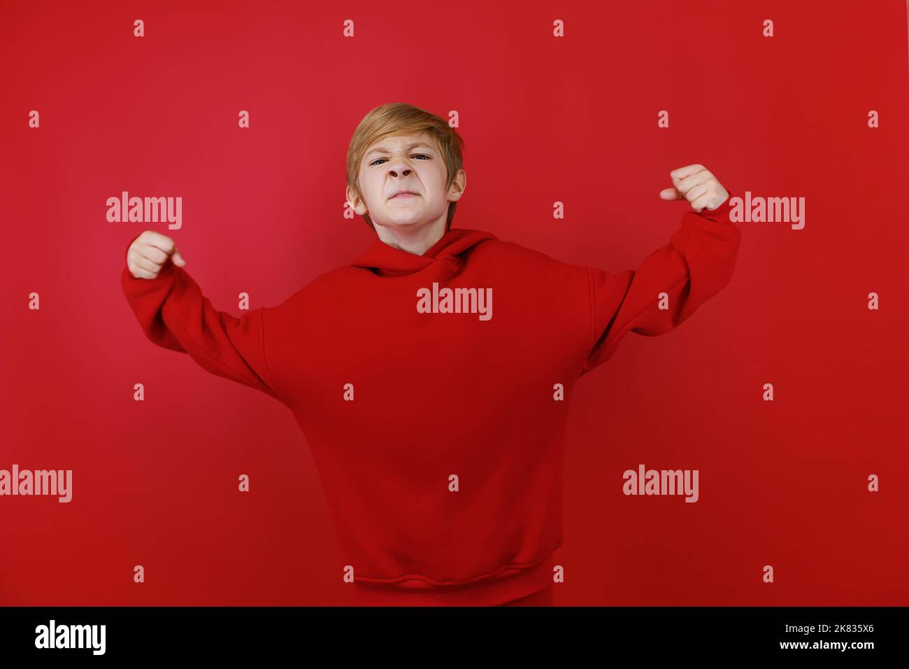 a boy in a red suit raised his hands up and clenched his fists Stock ...