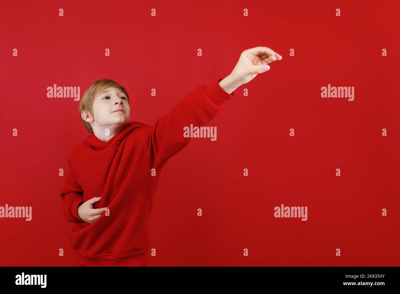 A cheerful boy in a red suit stretched his hand forward and tries to ...