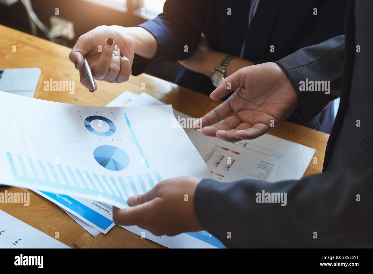 An auditor holds a pen pointing to documents to examine budgets and ...