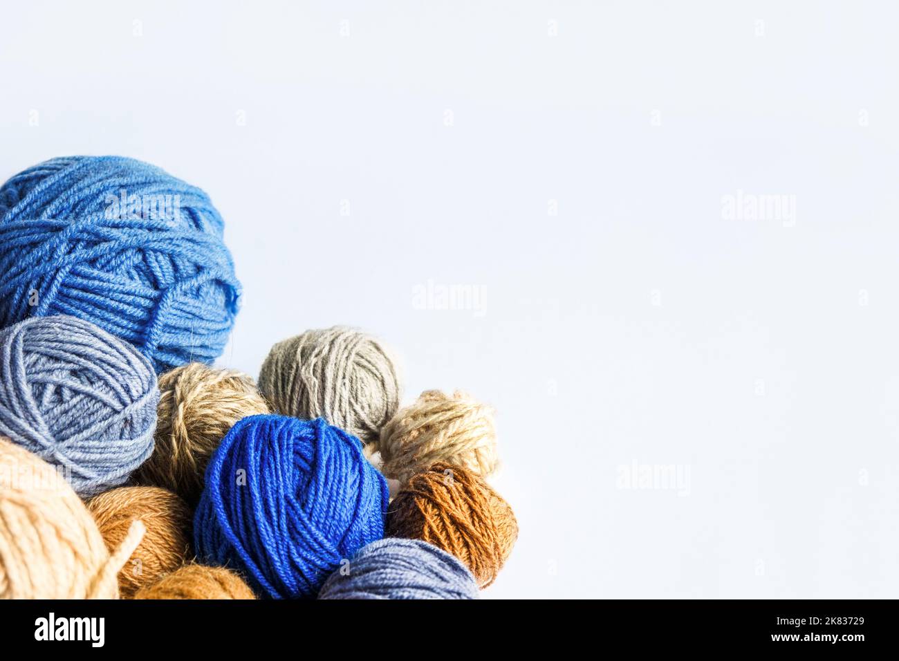 Blue, gray and brown balls of knitting thread on a blue background for ...