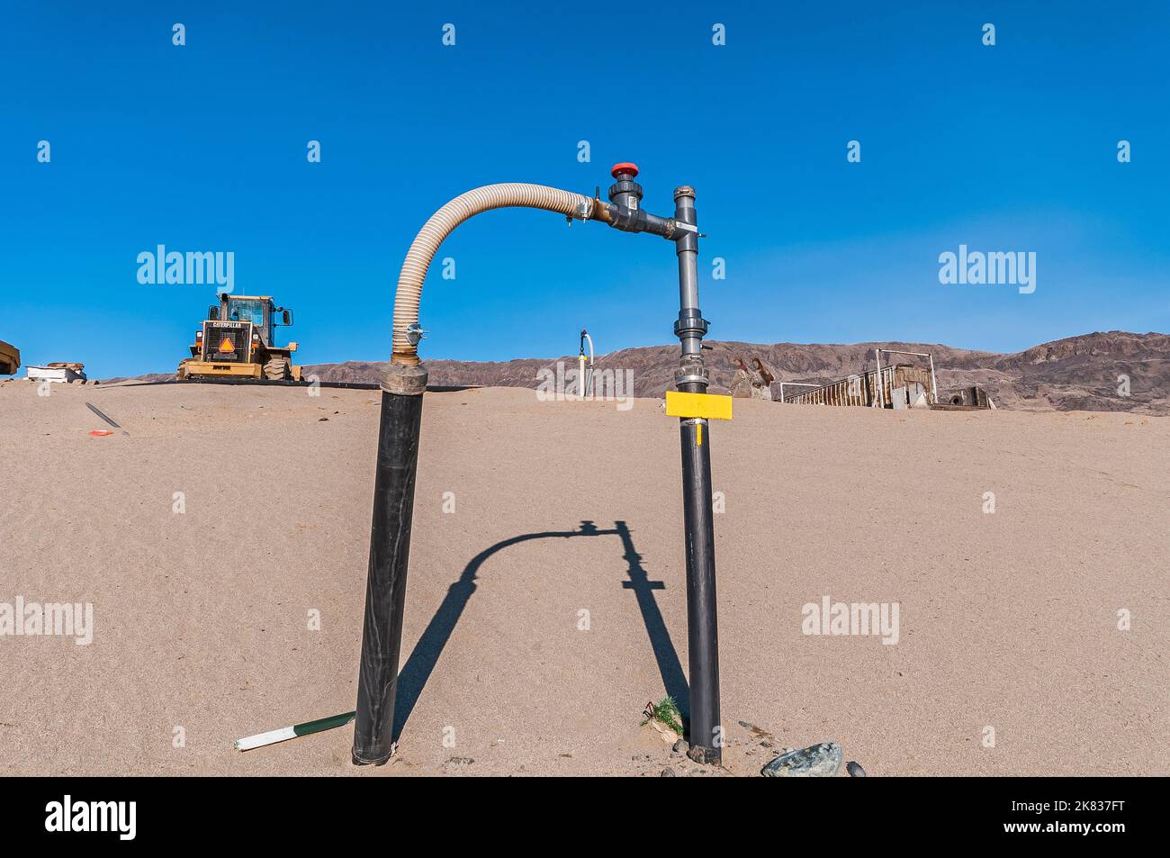A vertical methane wellhead framing a distant vertical methane wellhead ...