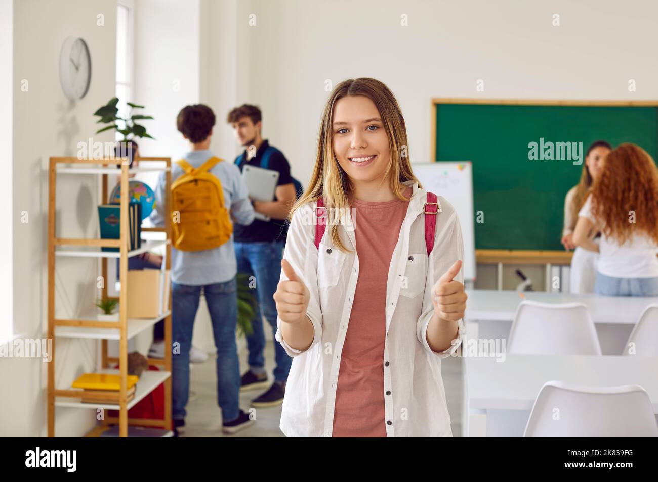 Happy school, college or university student standing in classroom and ...