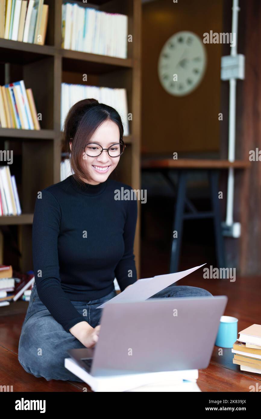 A portrait of a young Asian female student with a smiling face using a ...