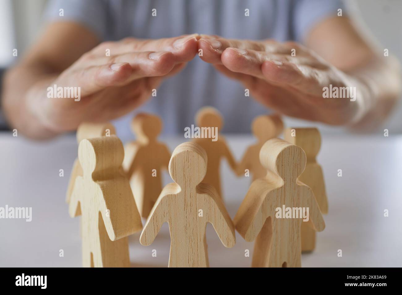 Woman covering her palm wooden figures of people protecting them, world ...