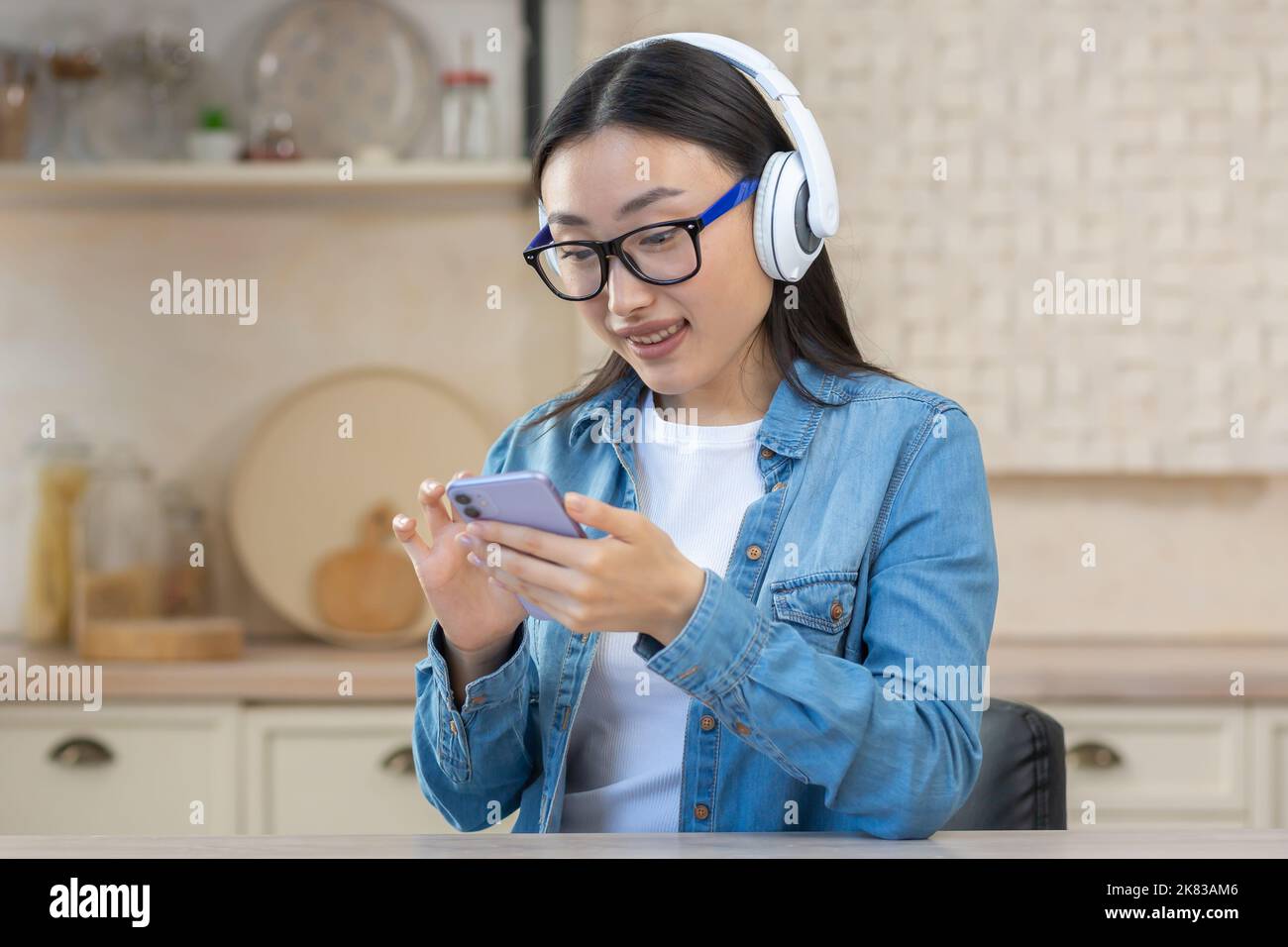 Young beautiful Asian woman listening to music on the phone. Sitting at ...